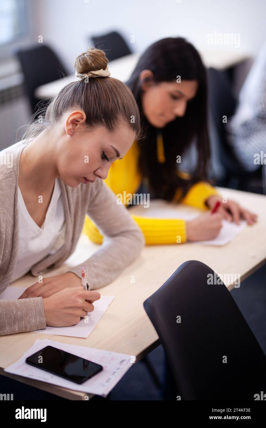 Students taking a test in a classroom. Smart young girls study at a ...