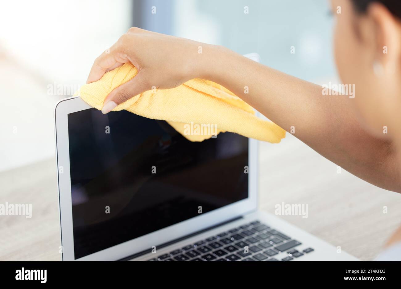 An unrecognizable woman cleaning her laptop in her apartment. One ...