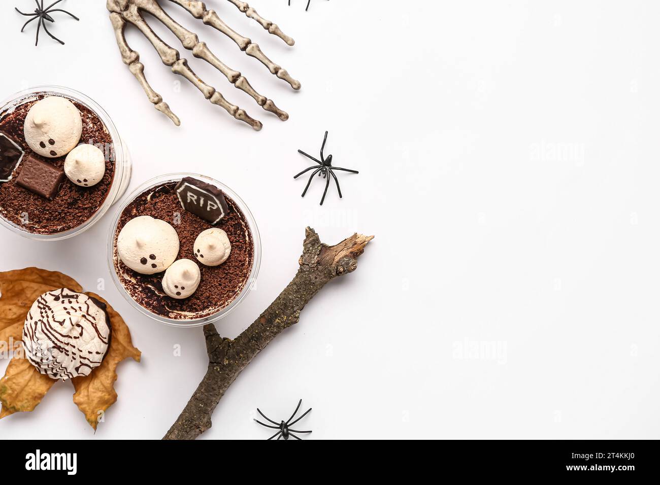 Plastic cups with delicious tiramisu, cookie, skeleton hand and spiders ...