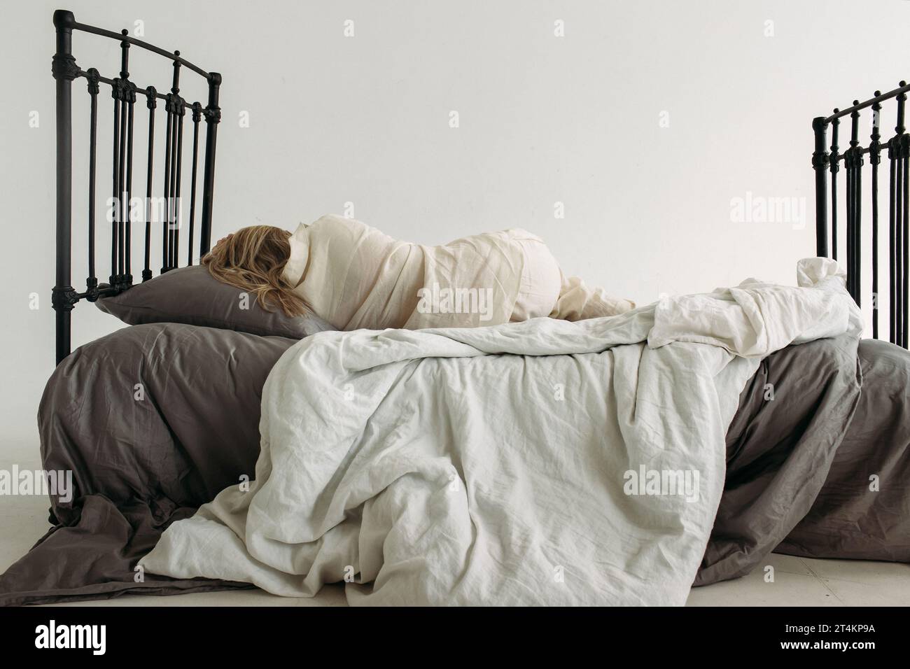 Frightened depressed woman lies alone on the bed with her back turned ...