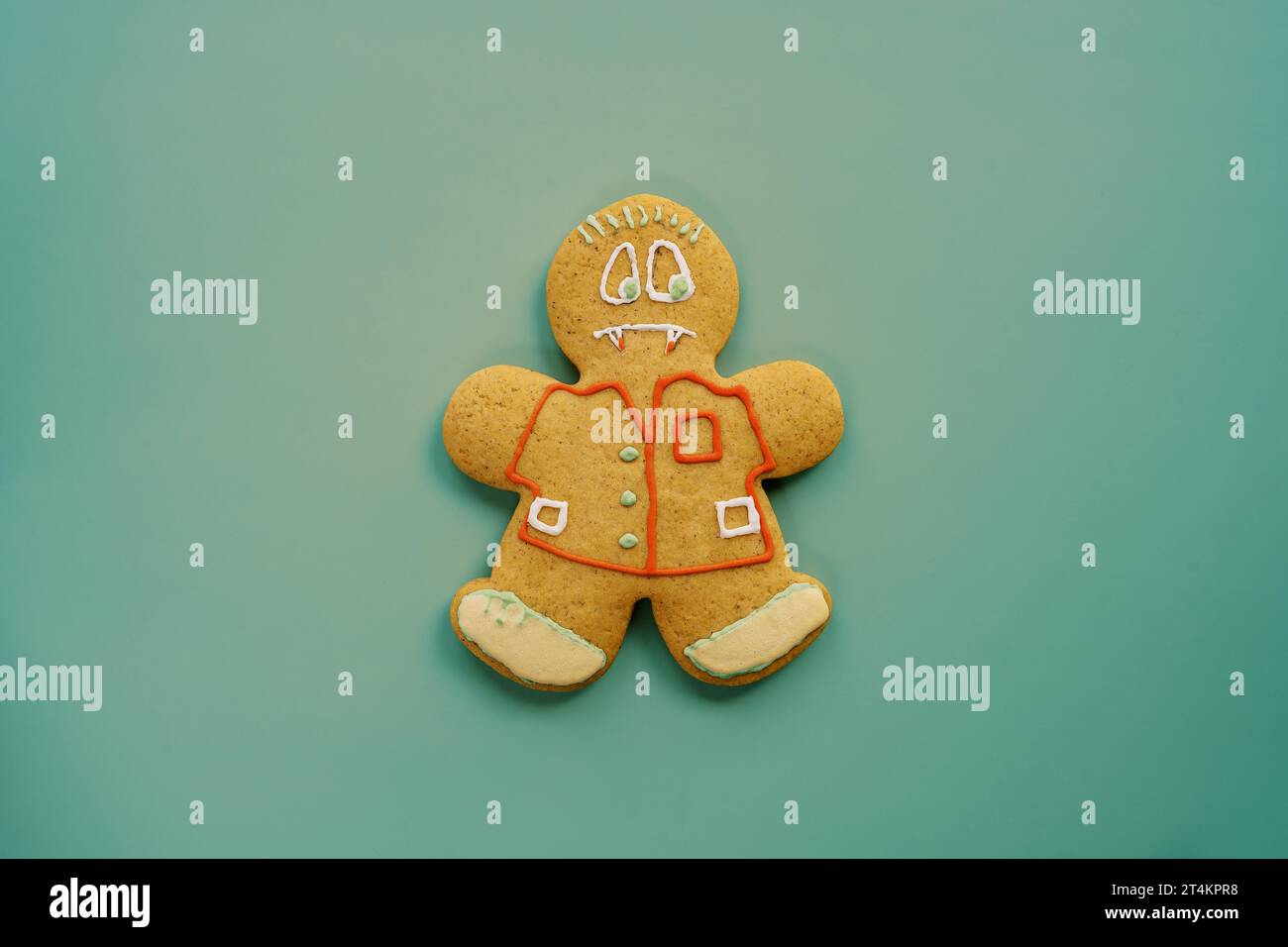 Glazed gingerbread man vampire lies centered on a green background ...