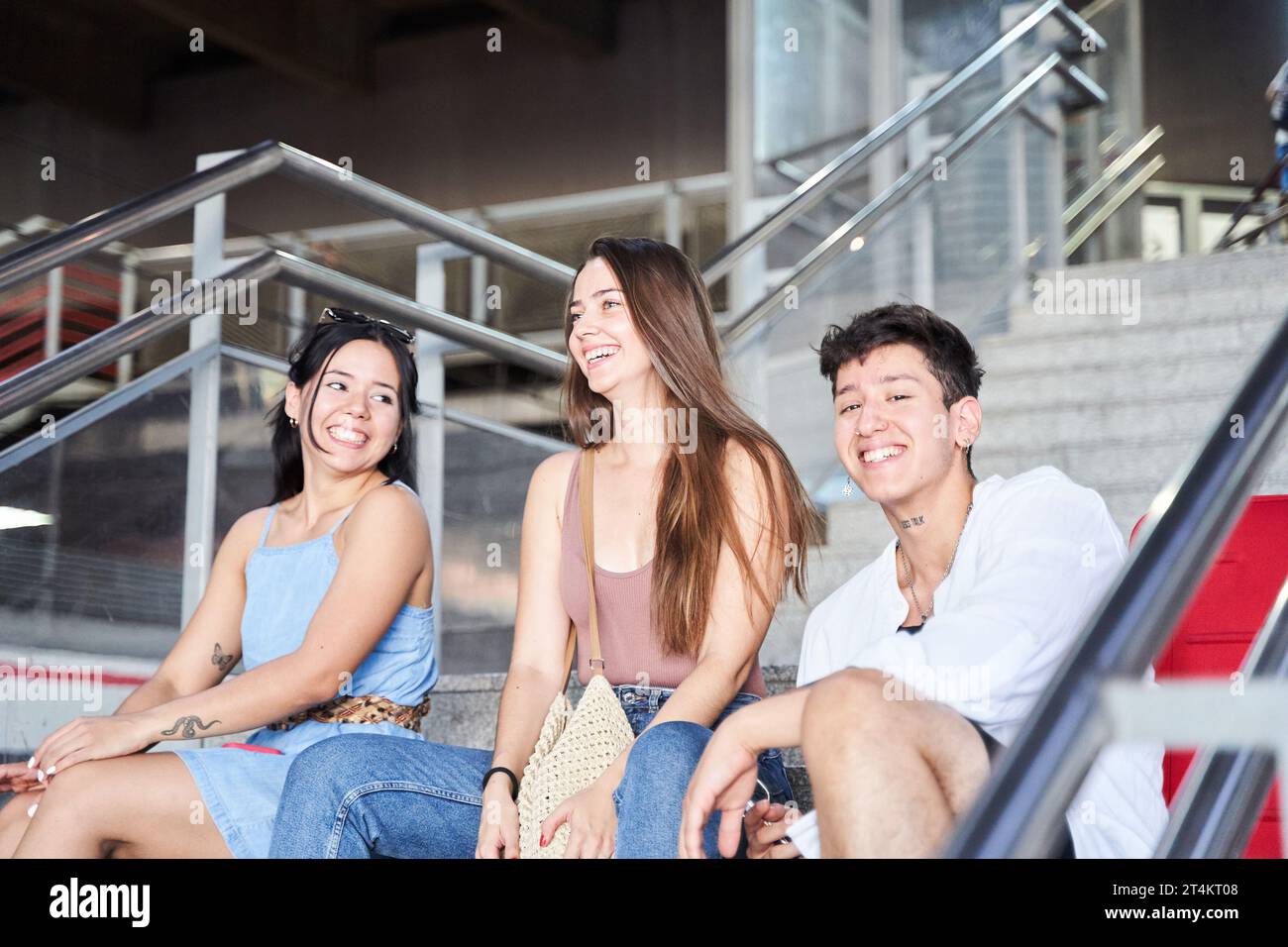 Portrait of diverse college friends sitting on station stairs - Happy ...