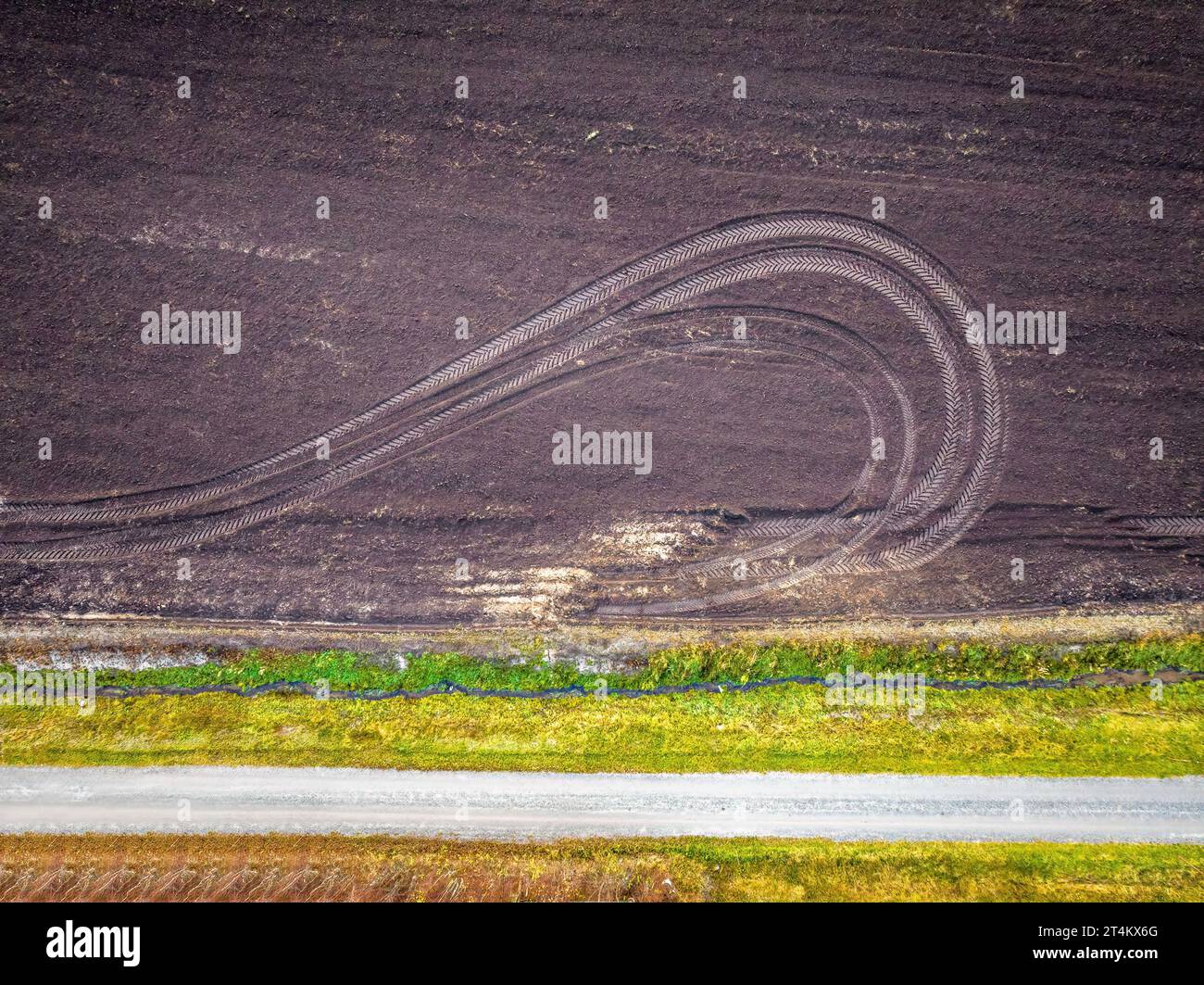 Tractor trace on fresh ploughed field, ditch and village road. Top down ...