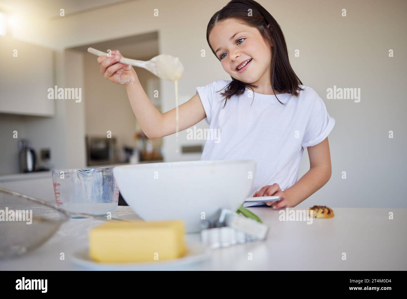 Happy little girl baking at home. Smart girl mixing ingredients to to ...
