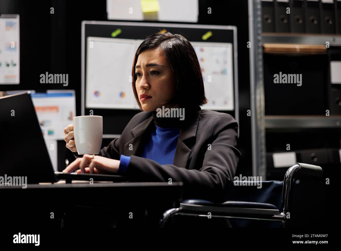 Paraplegic accountant businesswoman manager in wheelchair enjoying mug of coffee starting her ...