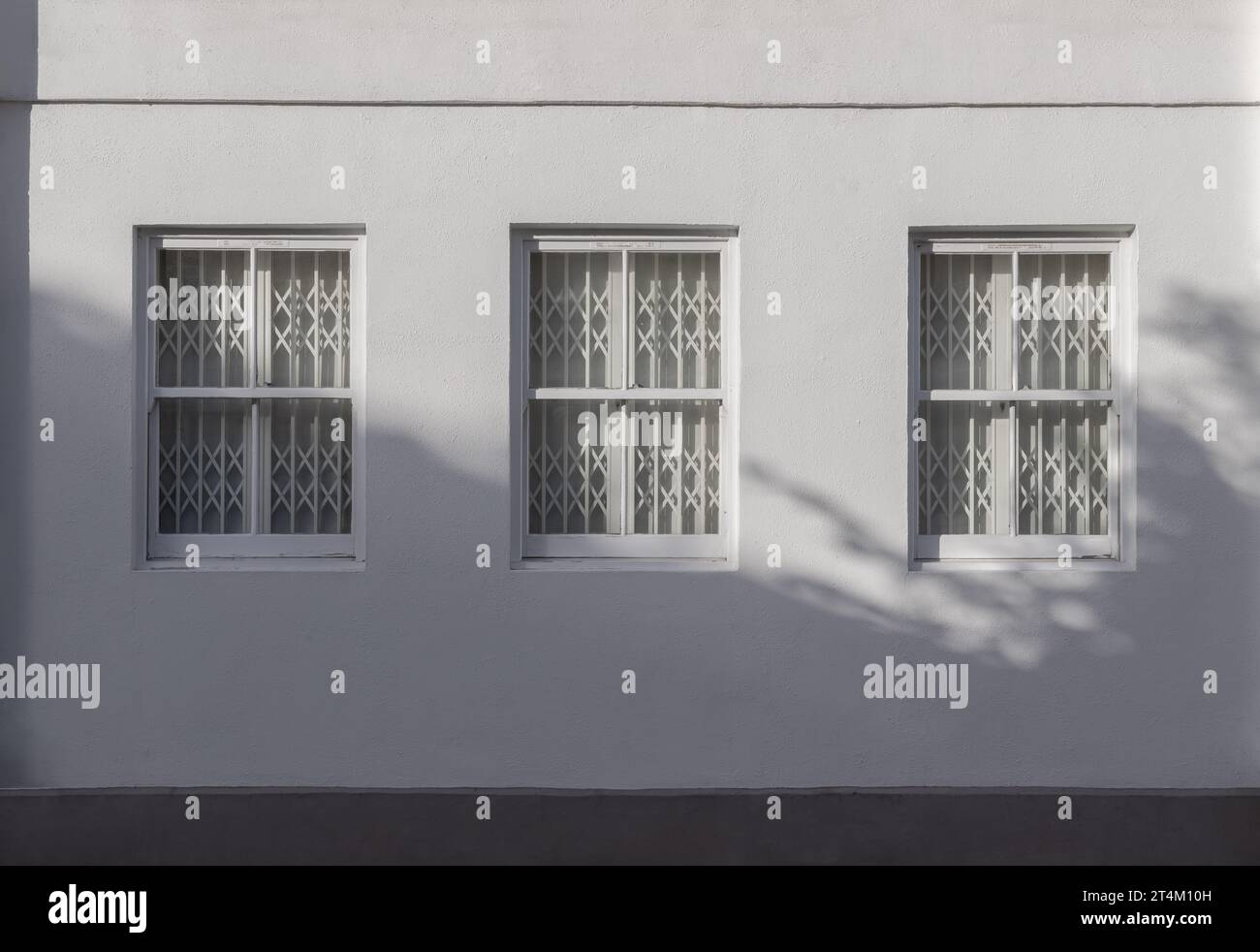 House exterior with triple wooden casement windows on white wall and ...