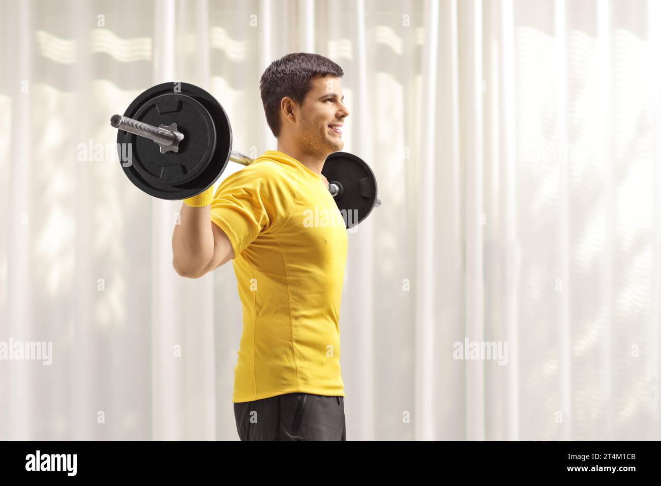 Man standing and lifting weights on shoulders at home Stock Photo - Alamy