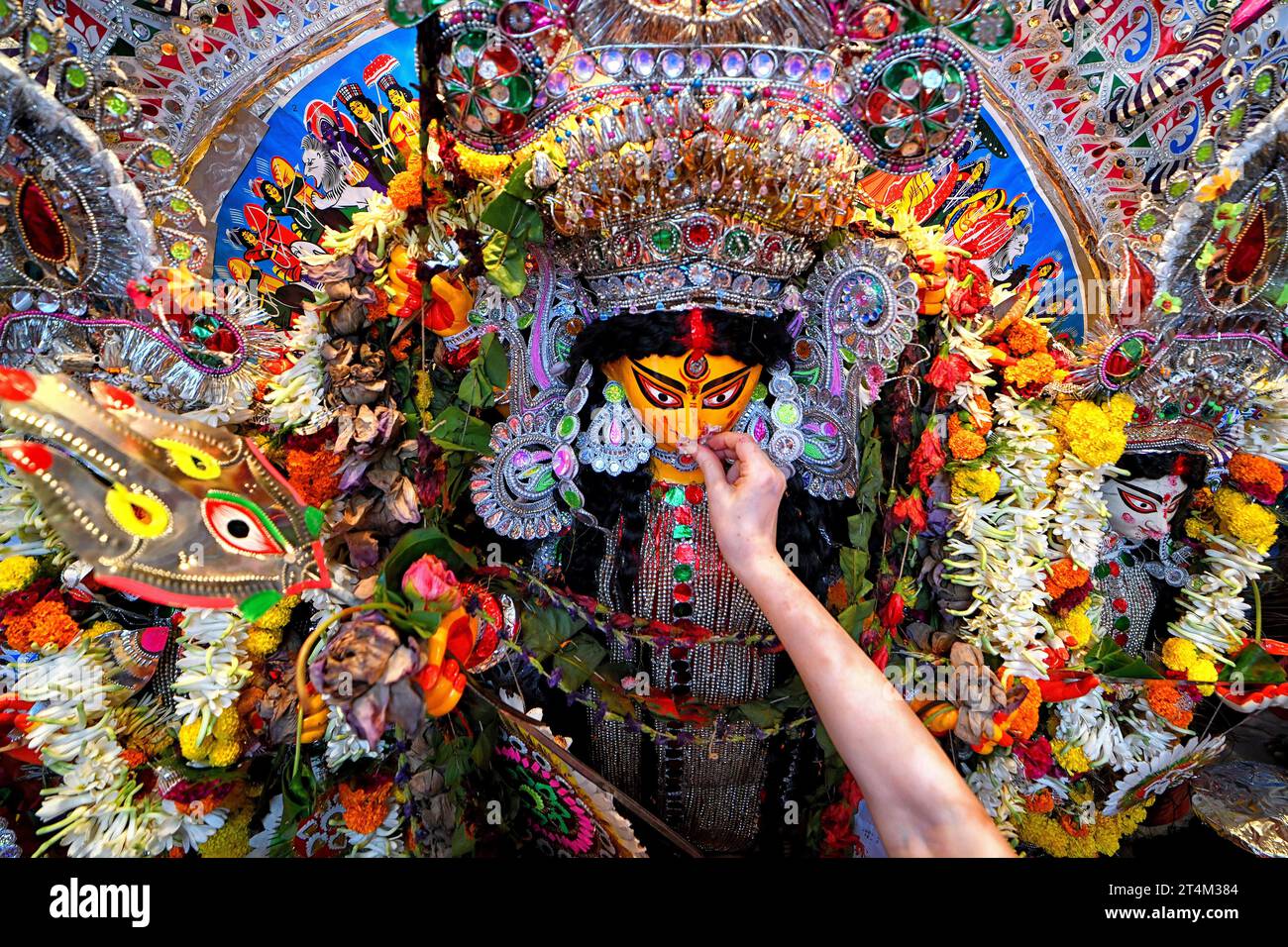 A Hindu devotee smears Devi Durga idol with vermillion powder as part ...