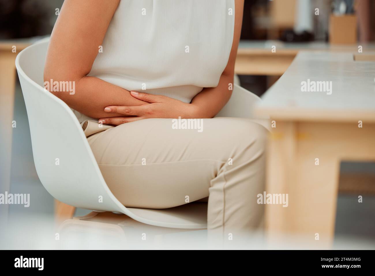 Closeup of one mixed race business woman holding sore tummy while ...