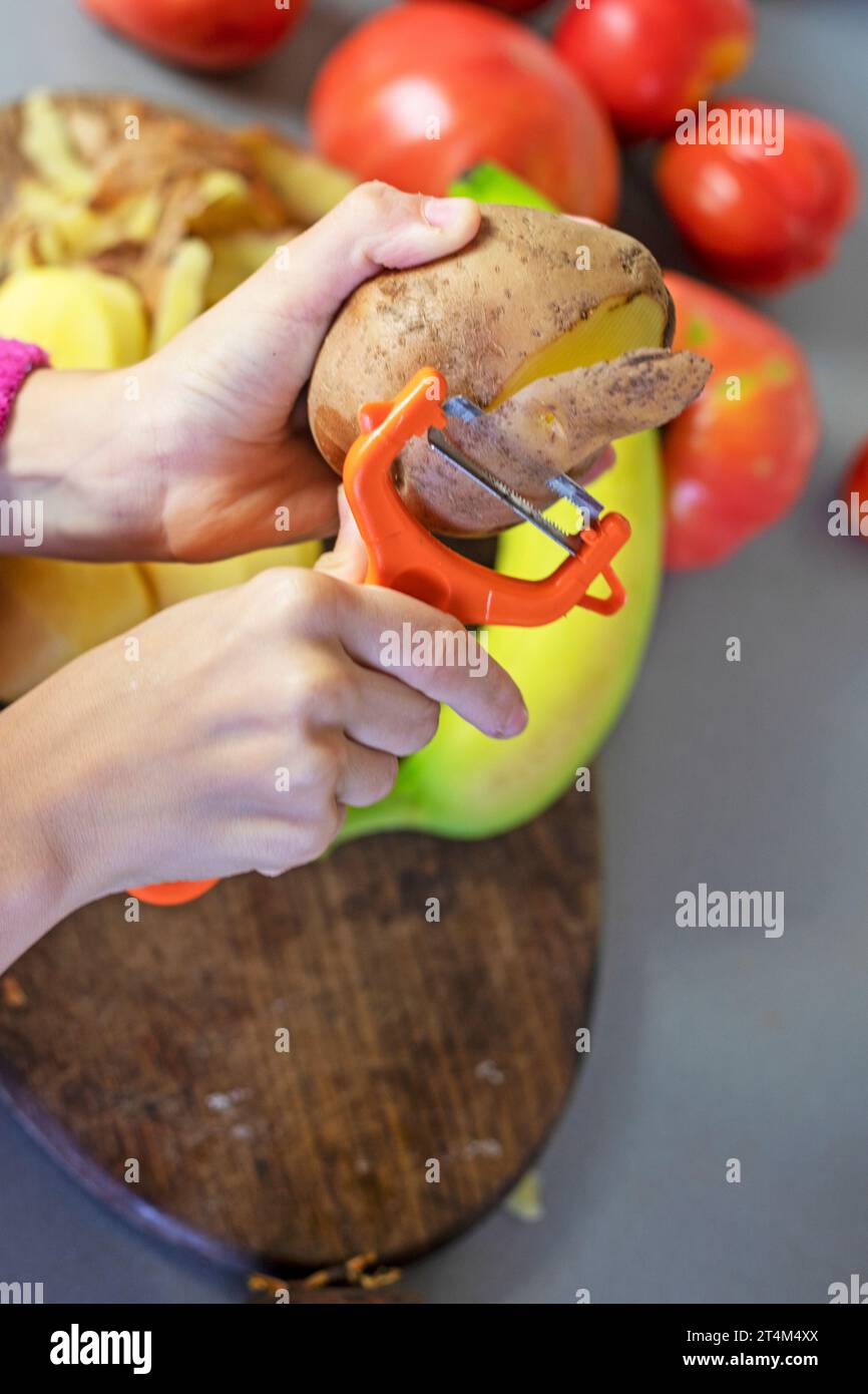 girl's hands peeling potato skins in the kitchen before cooking Stock ...
