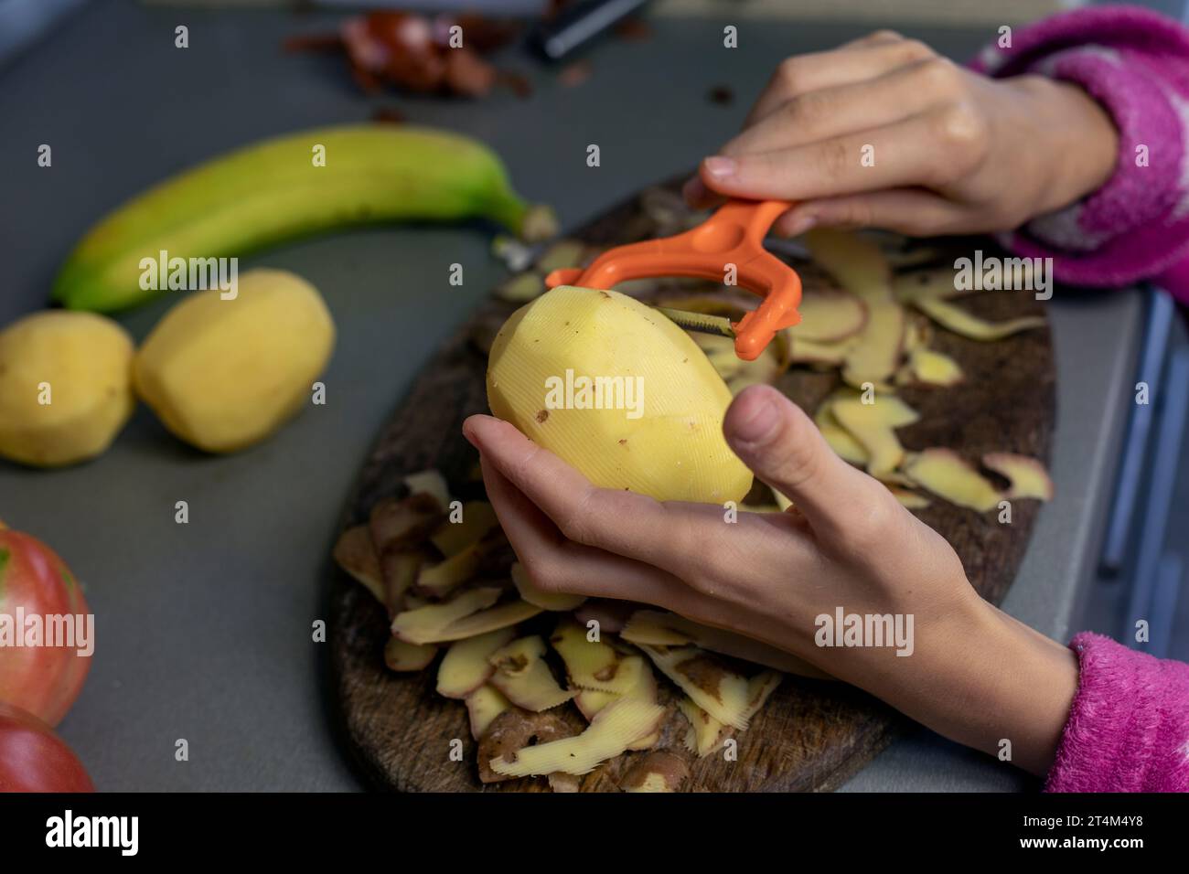 girl's hands peeling potato skins in the kitchen before cooking Stock ...