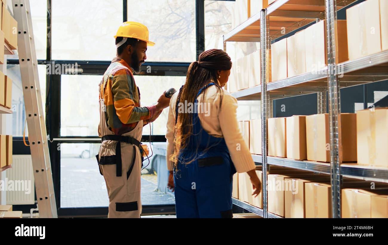 Team of employees scanning merchandise in depot, using scanner and tablet to check barcodes for ...