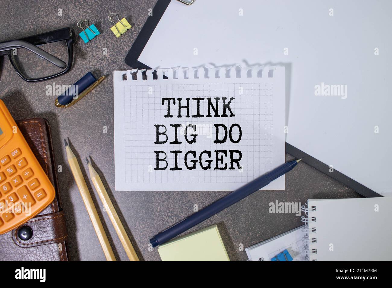 Text THINK BIG DO BIGGER on white paper on clipboard with chart and ...