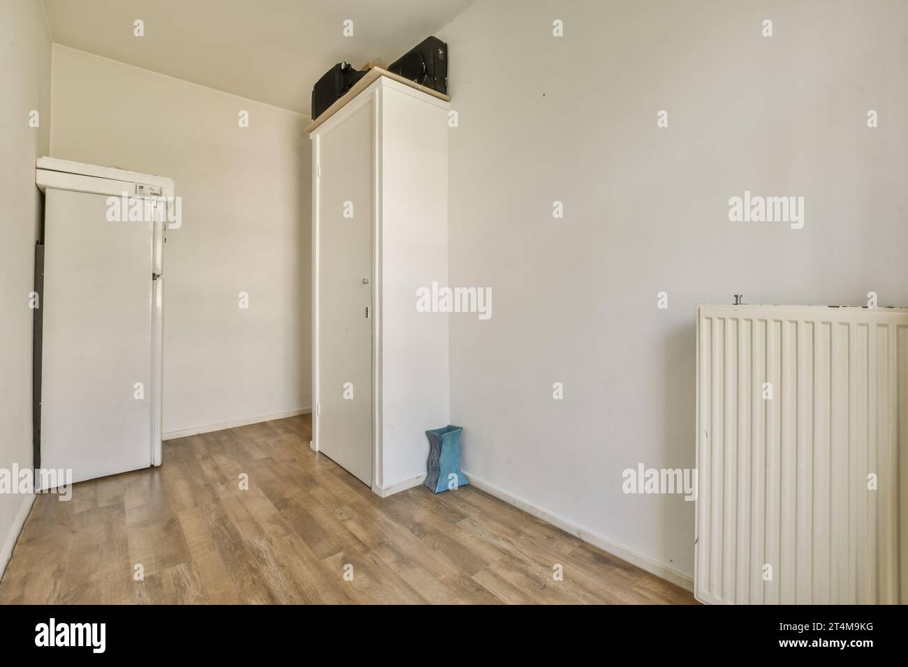 an empty room with wood floors and white walls, including a radiac ...