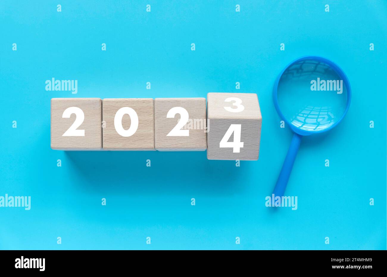 New year 2024 concept. Magnifying glass with a wooden cube with number ...