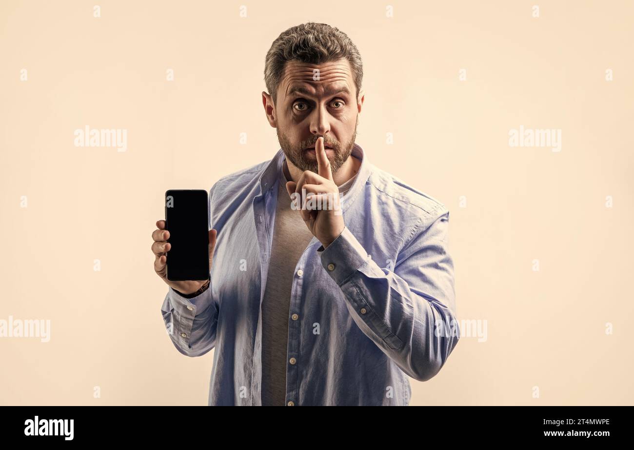 secret man showing phone app isolated on studio background. man showing ...