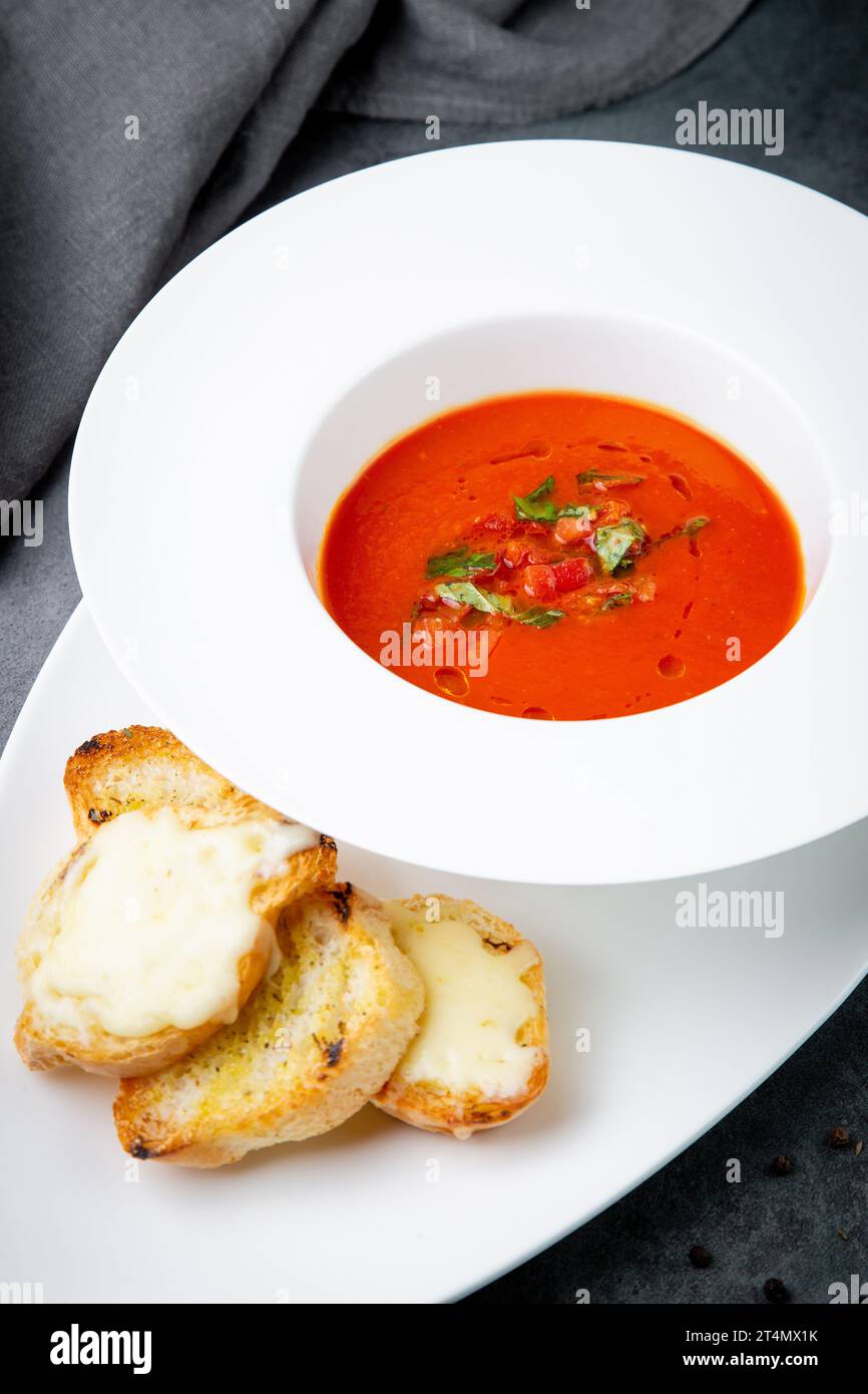 borscht with herbs in a white plate with pieces of bread, side view ...