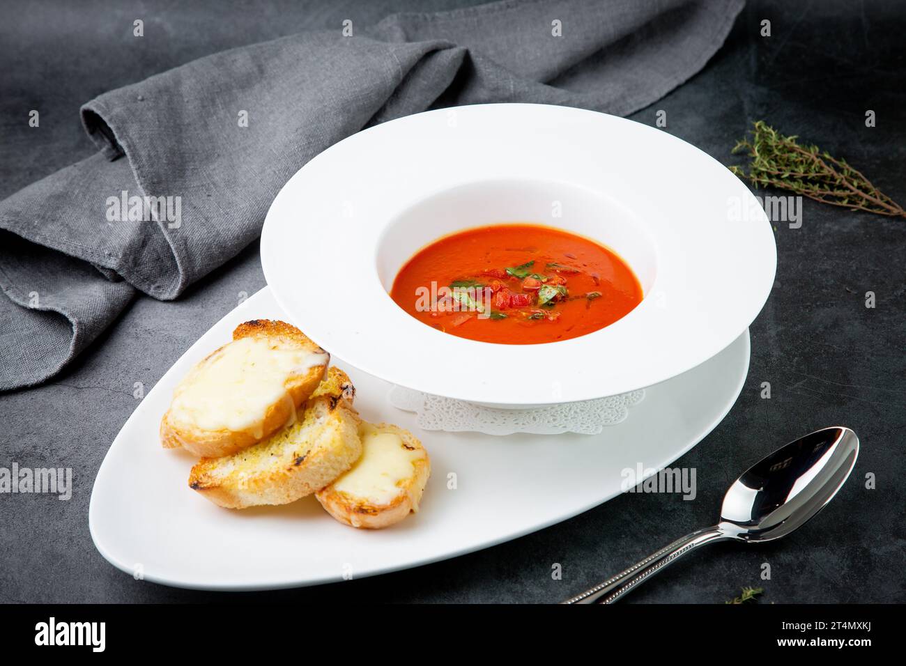 borscht with herbs in a white plate with pieces of bread, side view ...