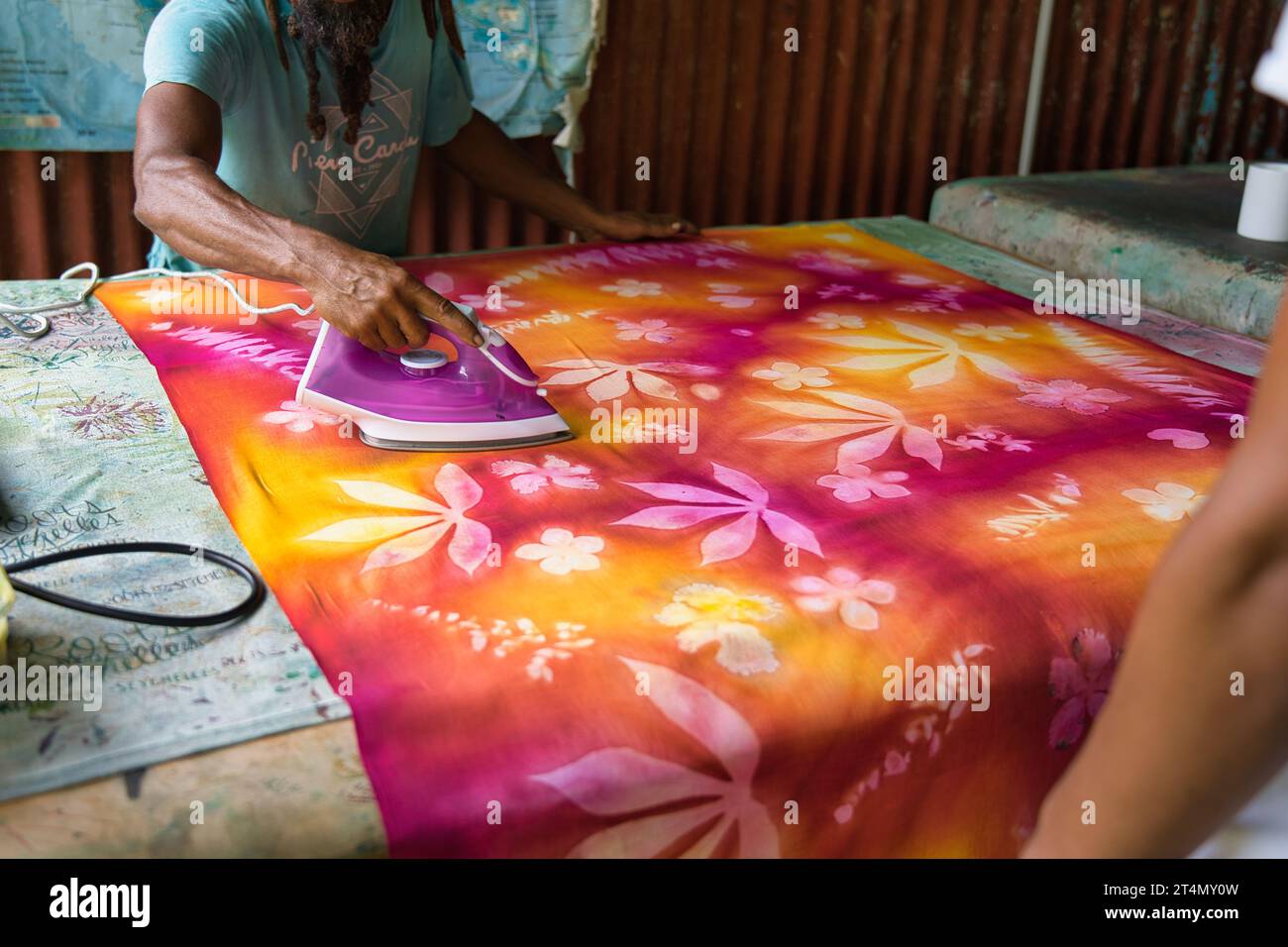 dark skin hand ironing with high heat the pareo to seal the printing ...