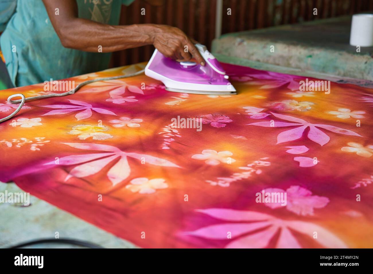 dark skin hand ironing with high heat the pareo to seal the printing ...