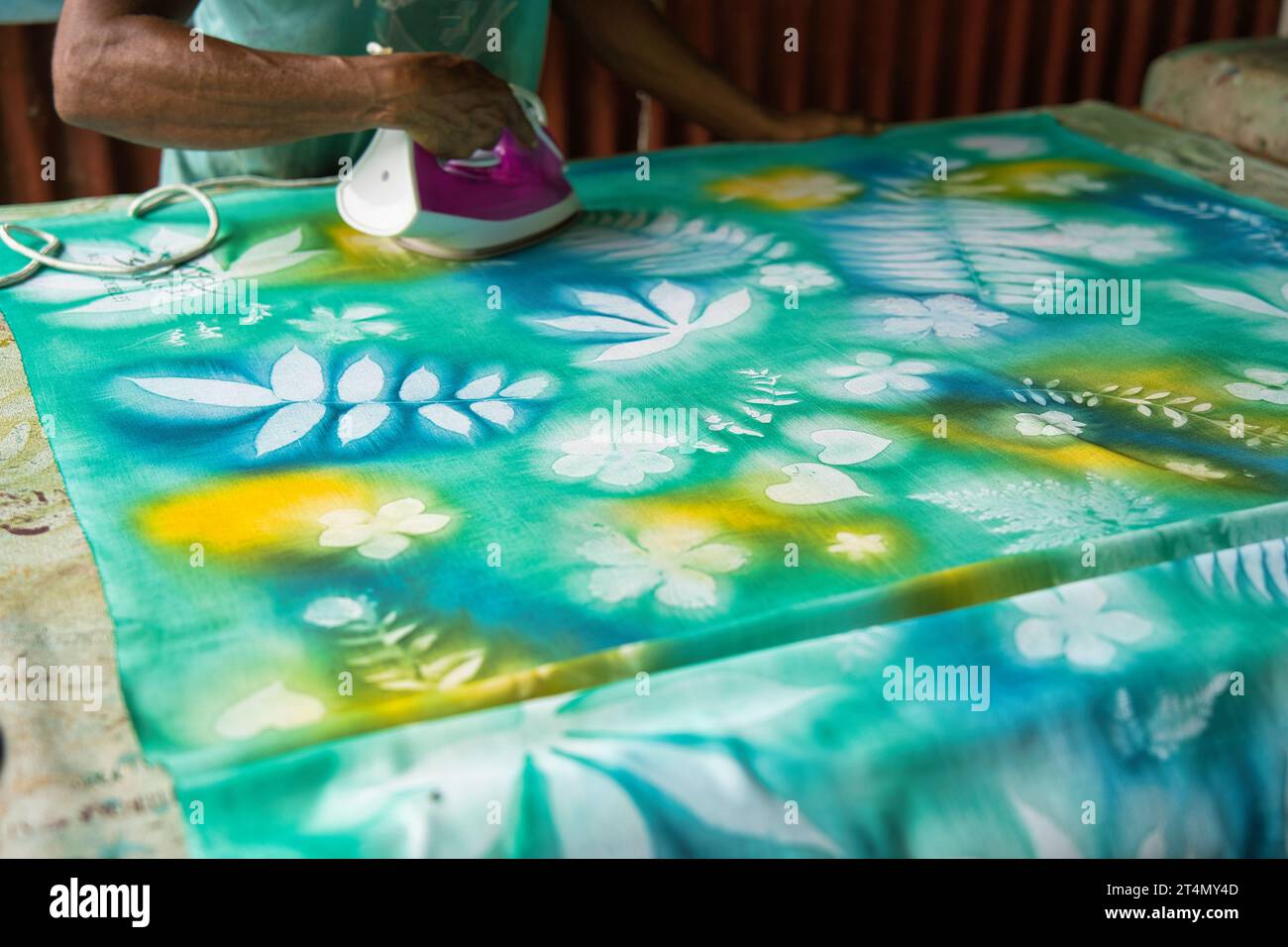 dark skin hand ironing with high heat the pareo to seal the printing ...