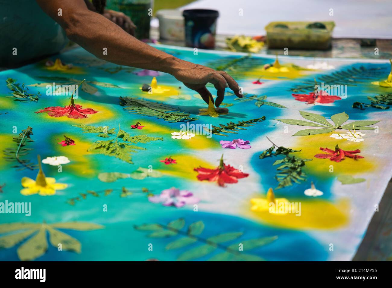 Dark skin man hand fixing pebble over the flower, painting with cloth ...