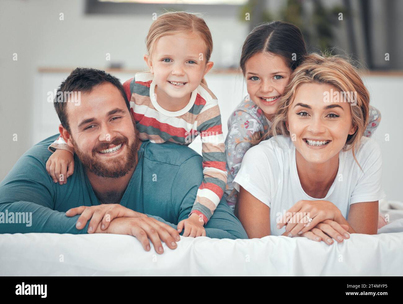 Happy caucasian family of four in pyjamas cosy together in bed at home ...