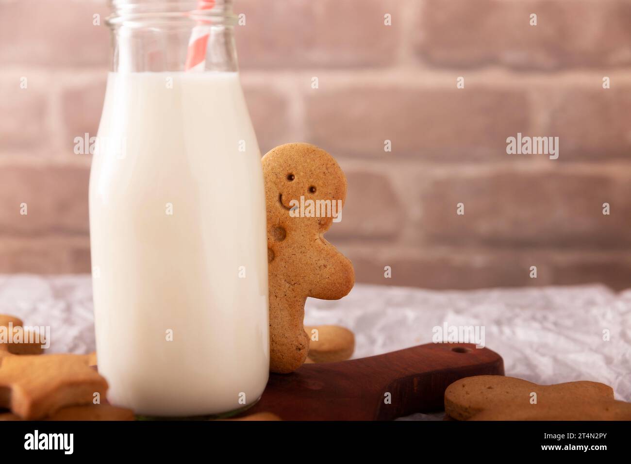 Homemade smiling gingerbread man cookie peeking out from behind a milk ...