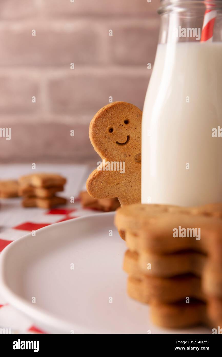 Homemade smiling gingerbread man cookie peeking out from behind a milk ...