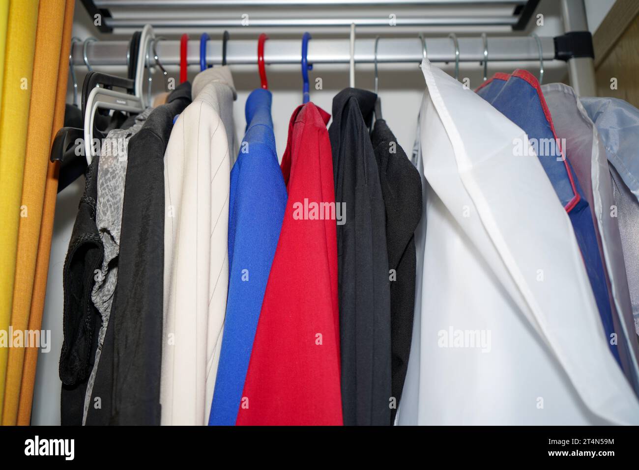 Wardrobe overflowing and colorfully mixed with jackets and pants ...