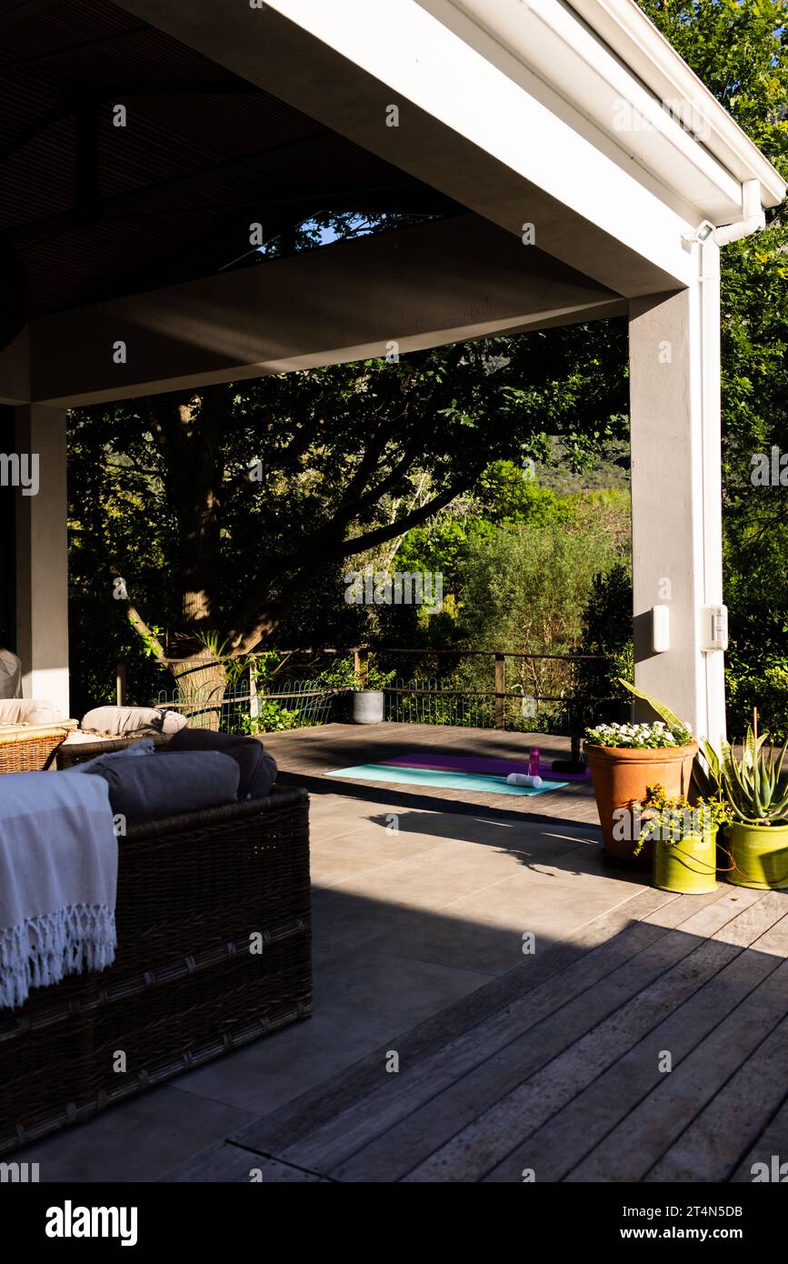 Outdoor furniture on terrace and yoga mat on deck in sunny garden, copy ...