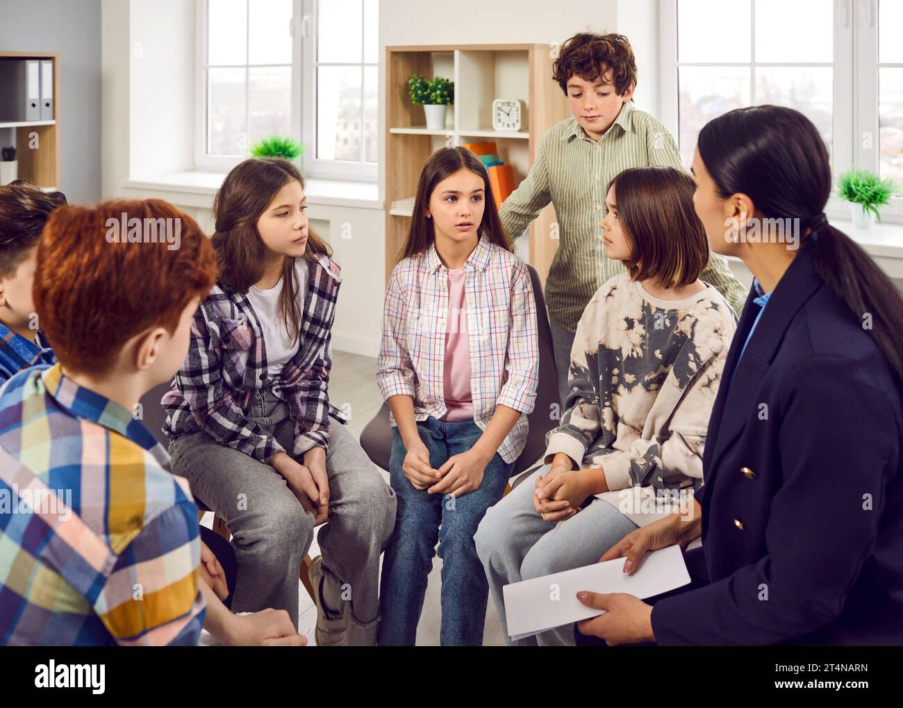 Group of school children together with their teacher discussing a sad ...
