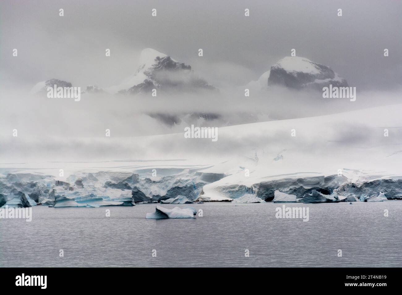 icebergs in front of cloud and snow covered mountains and ice cliffs of ...
