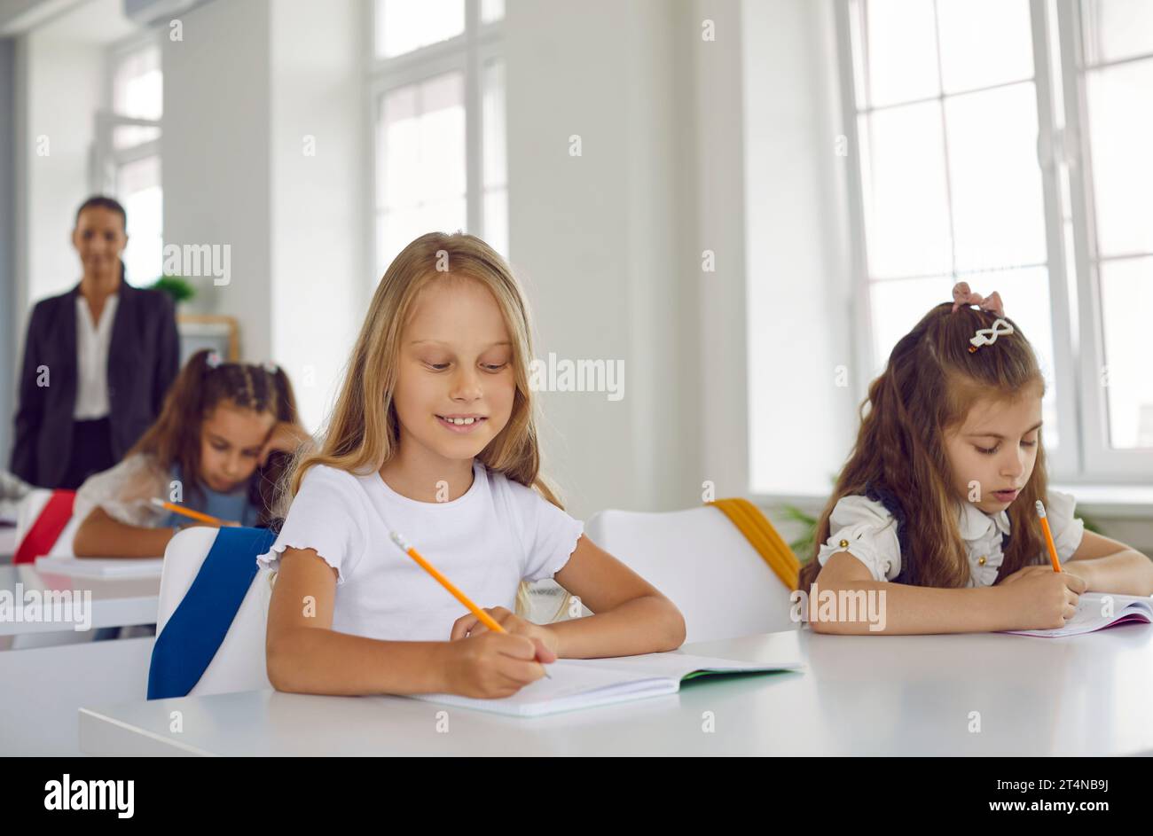 Elementary school children sitting in the classroom and writing in ...