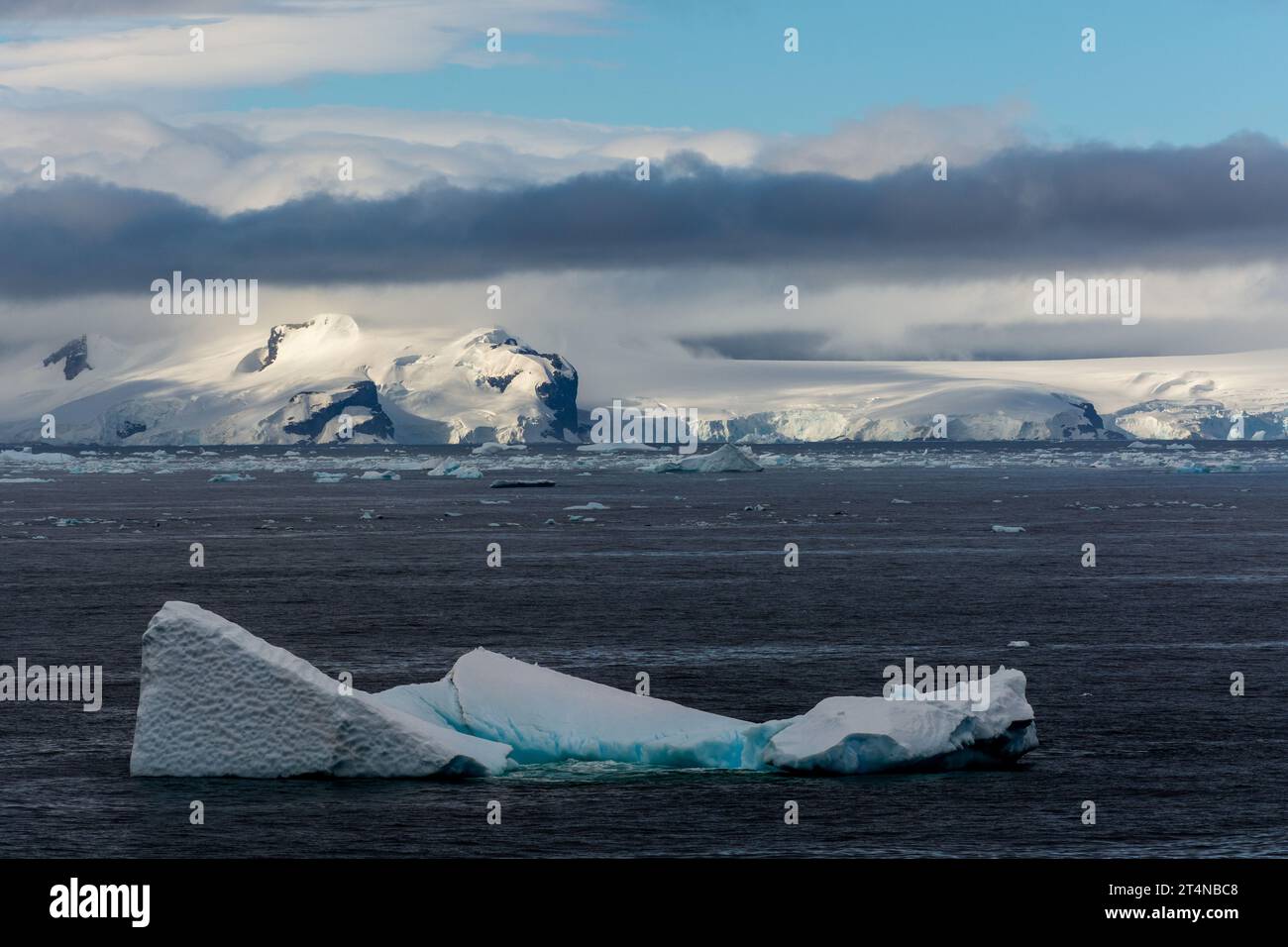 icebergs in waters in front of snow and cloud covered mountain ...