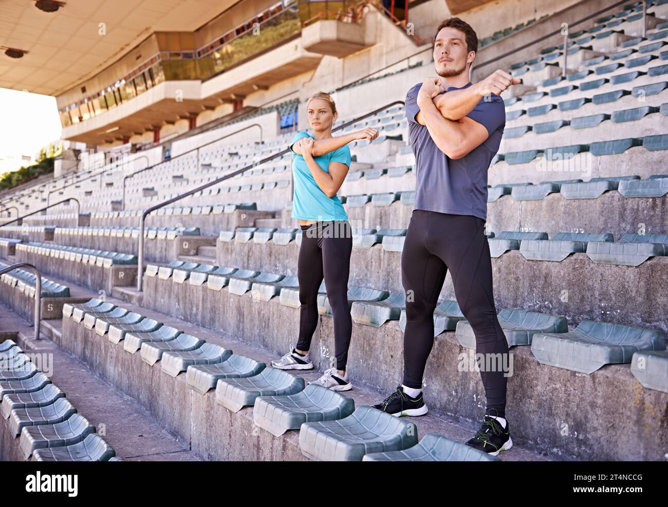 Doing a team stretch. two young people stretching at an athletics arena ...