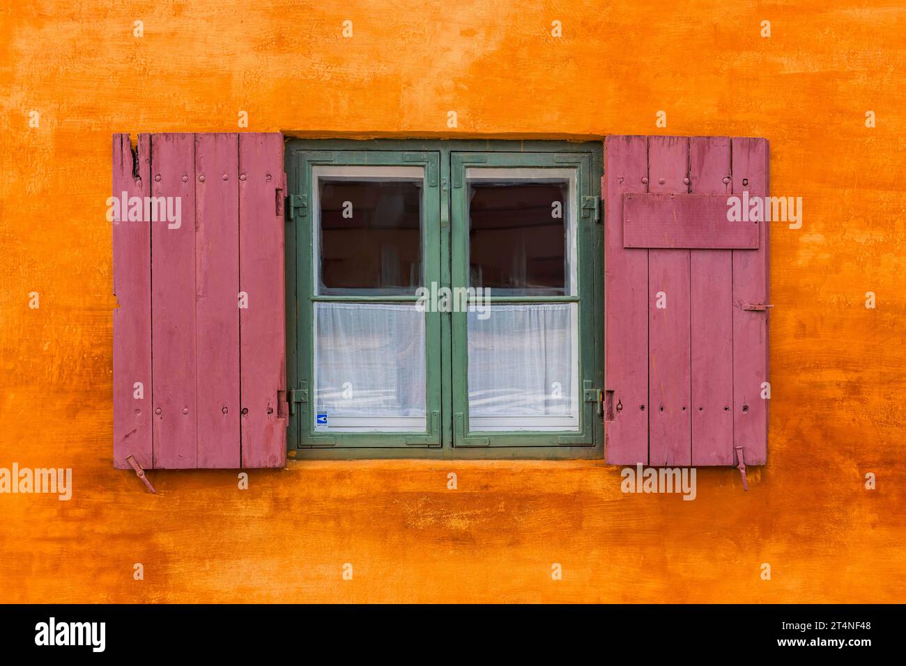 Wooden window with window flaps in front of orange facade, colourful ...