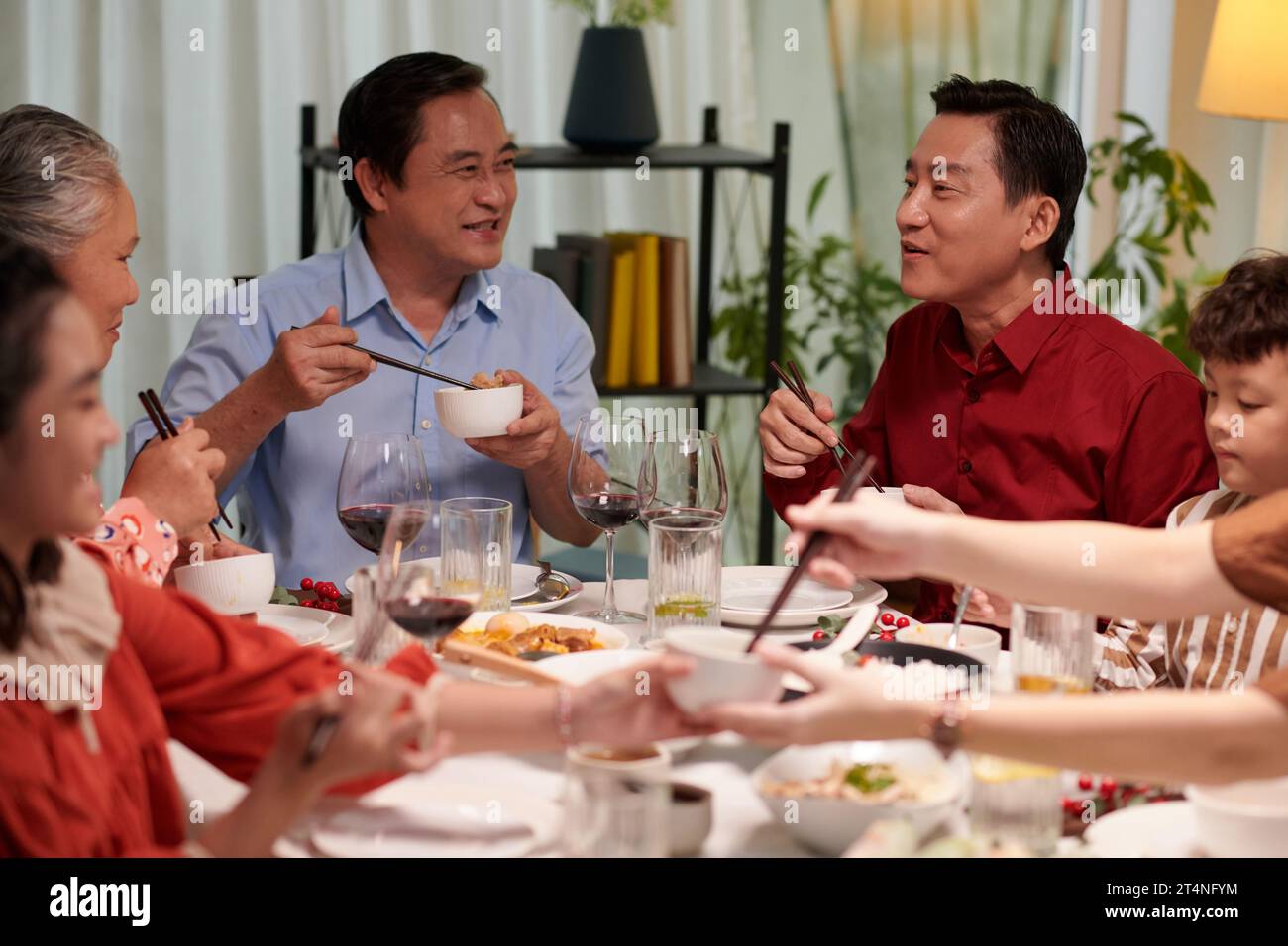 Vietnamese family members eating traditional dishes and discussing news ...