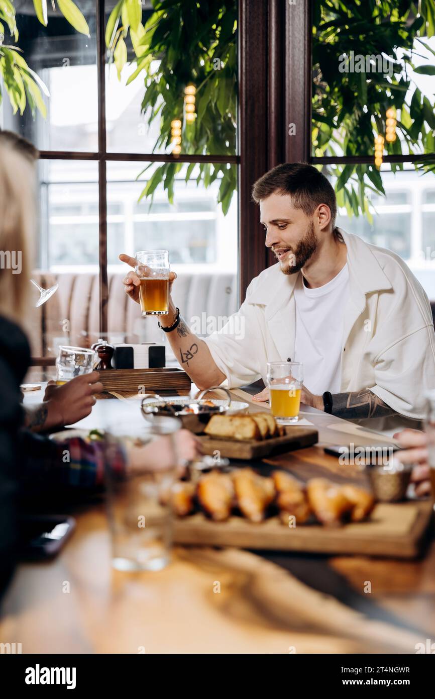 Happy young man drinking draft beer while having fun in pub or bar with ...