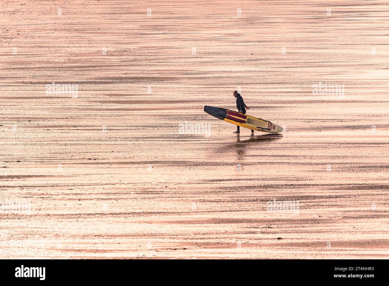 Evening light over a tired mature surfer dragging a Bennett Surf Rescue ...