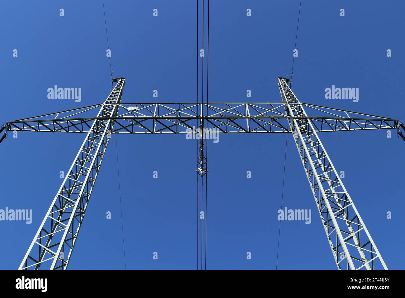 High voltage pylon standing against blue sky, industrial construction ...