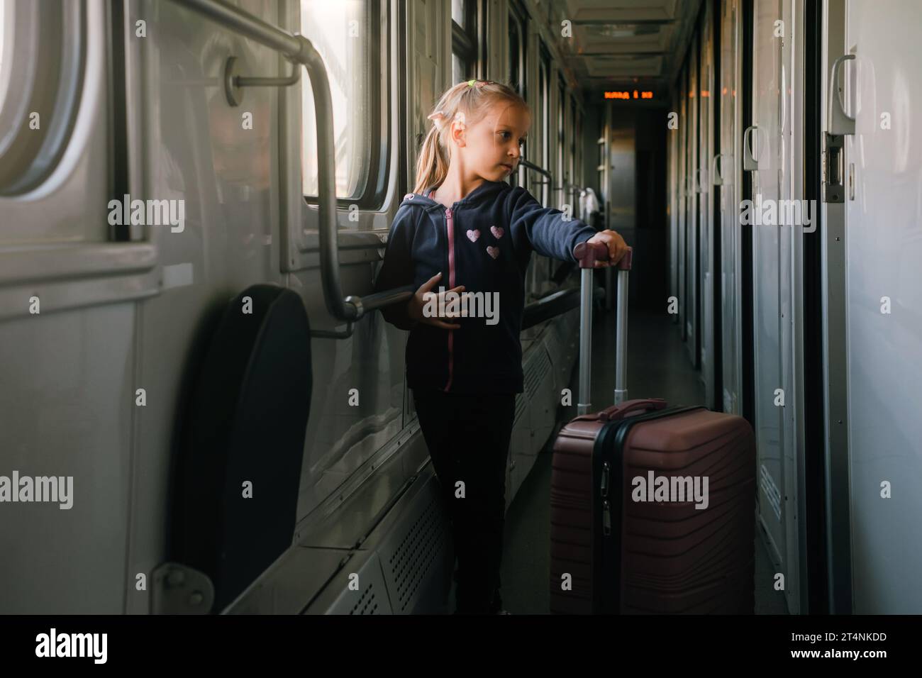 Toddler child looking through train window on sunset, bright sunlight ...