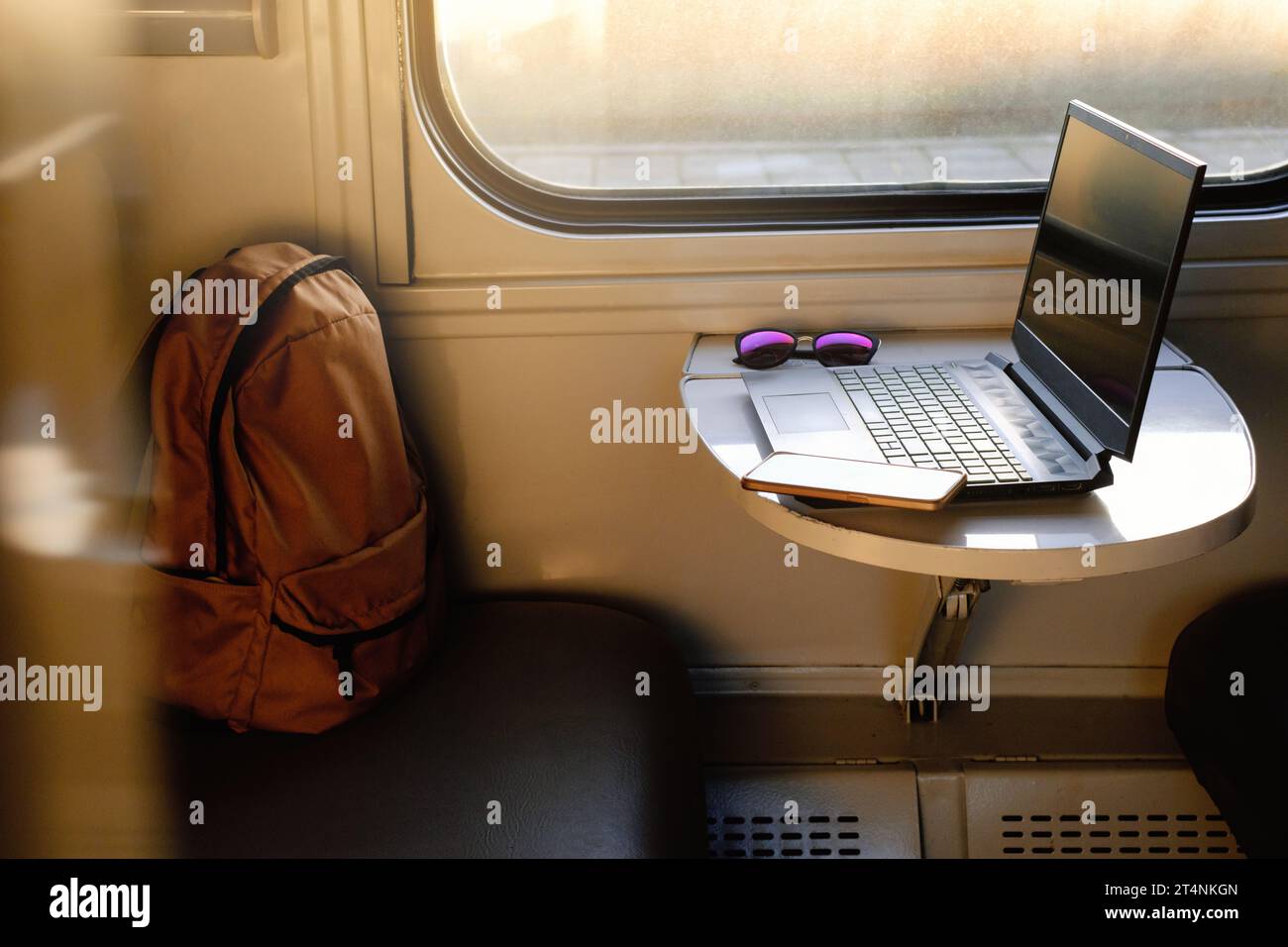 Working in train on sunset. Laptop standing on the table by the window ...