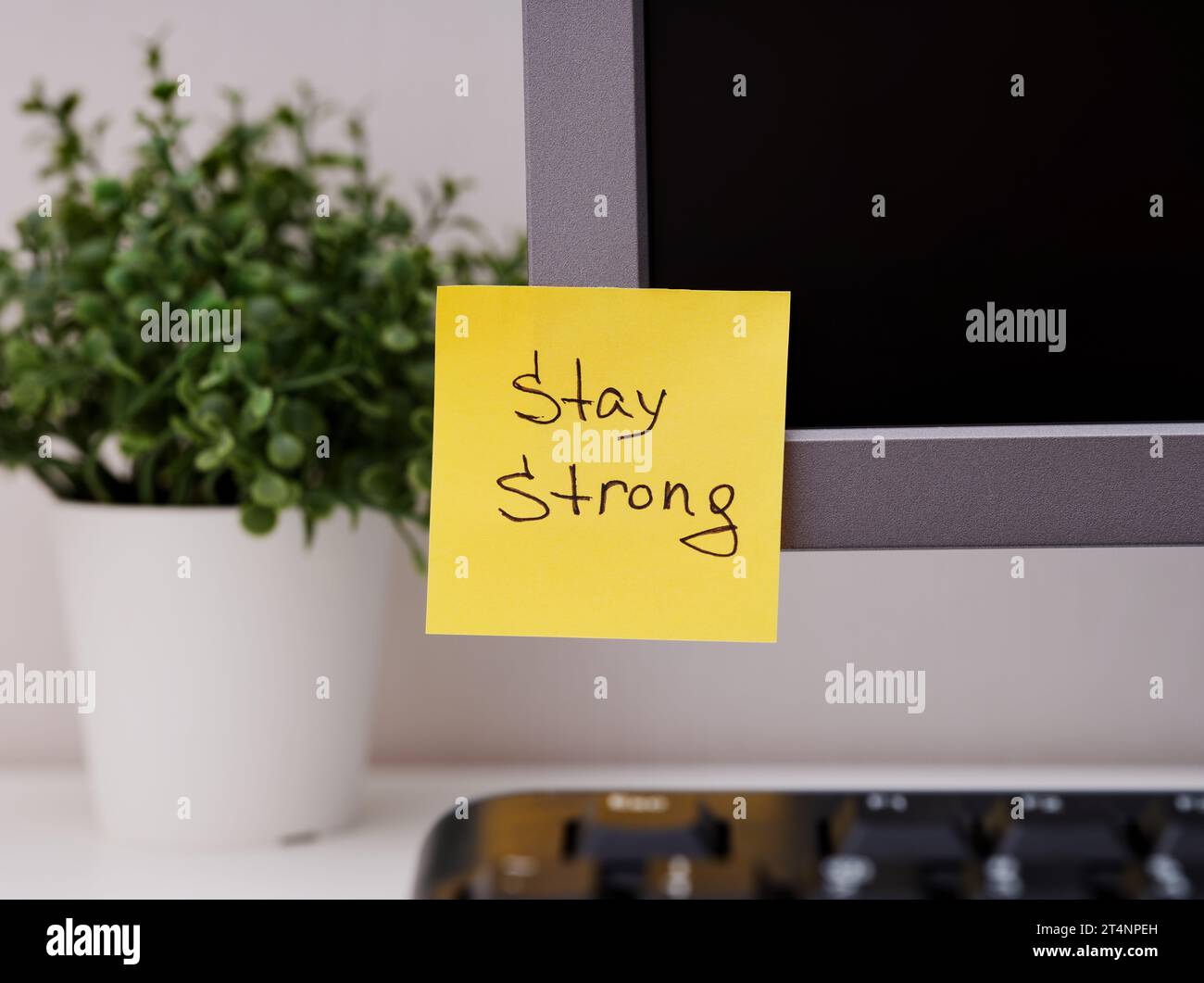 A yellow paper notes with the reminder Stay Strong on it sticked on to ...