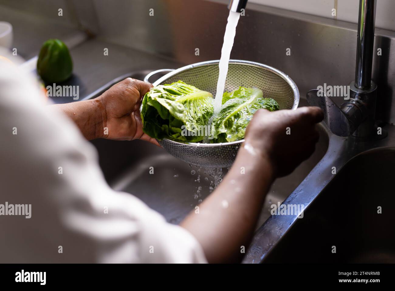 African american male chef washing vegetables in sink in restaurant ...