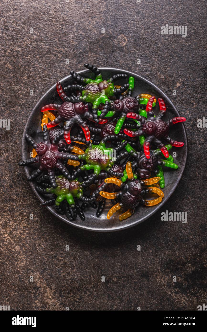 Scary sweet jelly spiders. Halloween candies on plate on the black ...