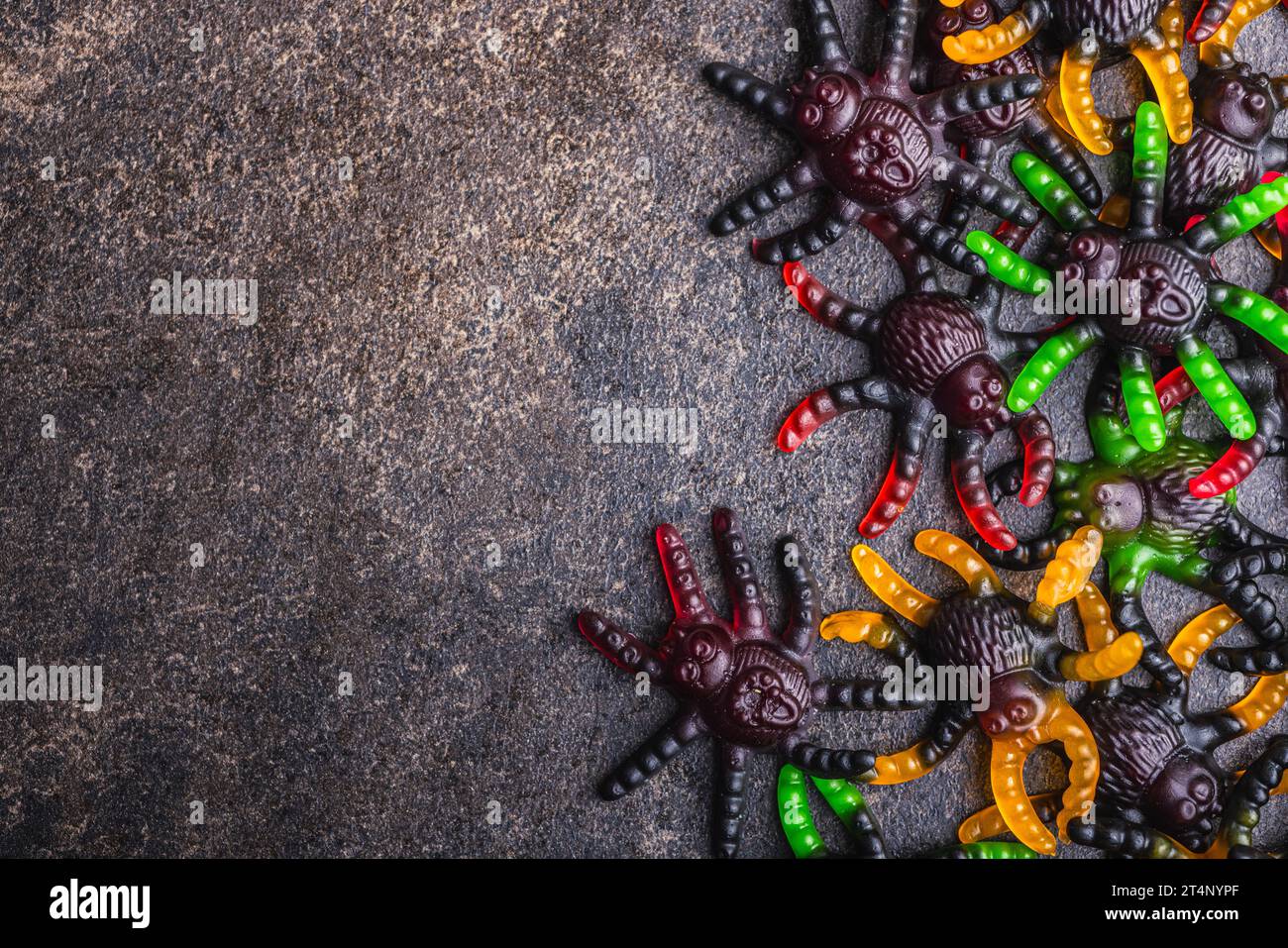 Scary sweet jelly spiders. Halloween candies on the black table. Top ...