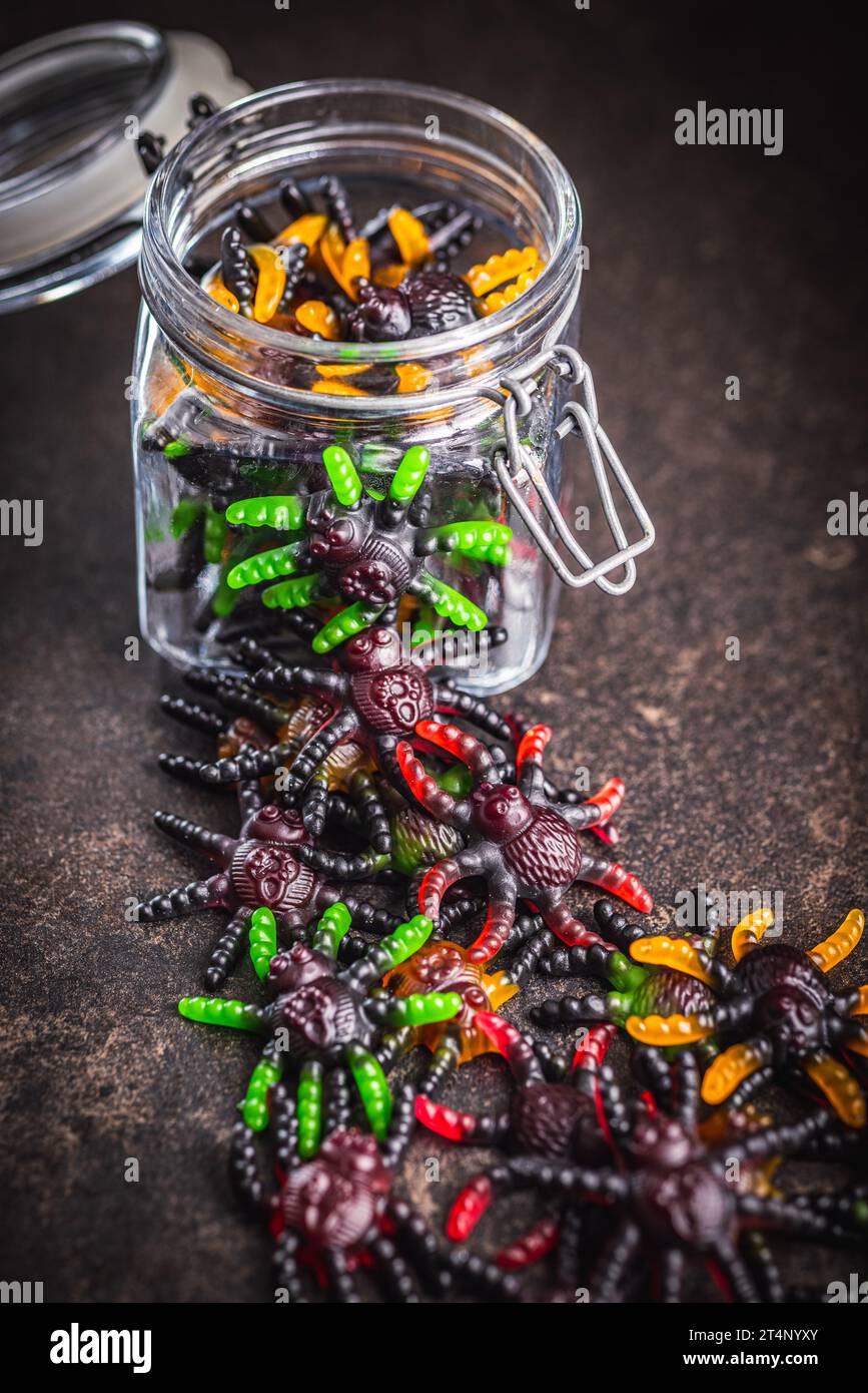 Scary sweet jelly spiders. Halloween candies in jar on the black table ...