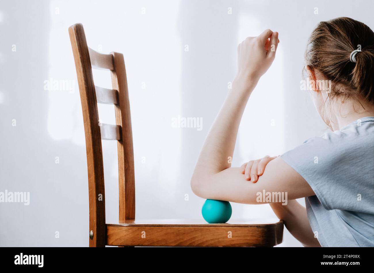 Woman doing triceps massage with therapy ball on wooden chair Stock ...