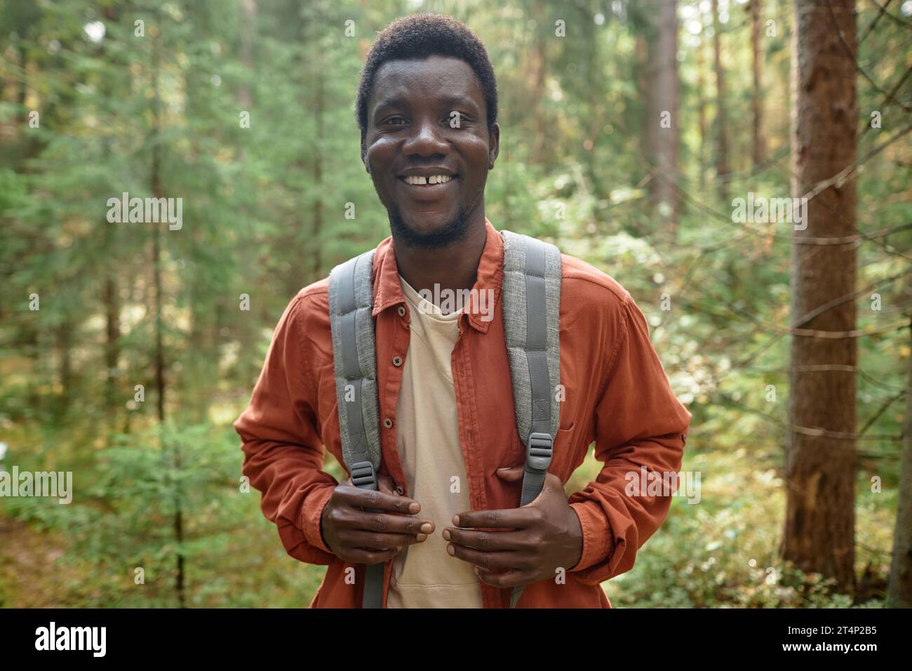 Portrait of African American hiker with backpack smiling at camera ...